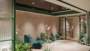 Um interior moderno com área de estar, um sofá estofado verde e diversas plantas.