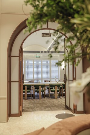 Um corredor interno com um arco de madeira que dá para um espaço com mesa e cadeiras de jantar.