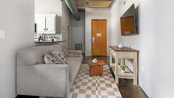 Um espaço de estar compacto com um sofá, uma mesa de madeira pequena e um tapete xadrez.