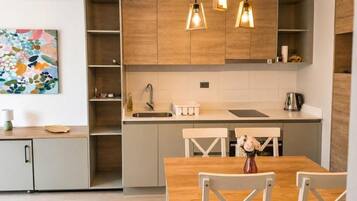 Cozinha moderna com armários de madeira, mesa de jantar com cadeiras e iluminação pendente.