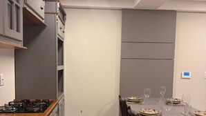 Cozinha moderna com fogão a gás, armários e área de jantar com mesa posta para quatro pessoas.