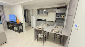 Cozinha compacta com área de jantar, televisão e um globo em uma estante.