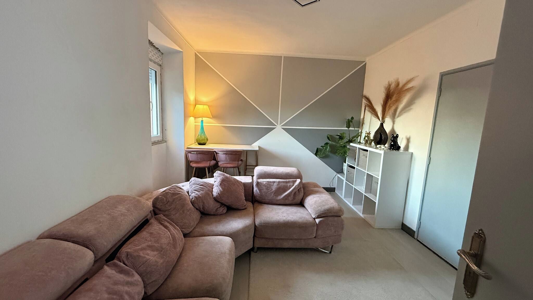 Uma sala de estar moderna com sofá seccional, uma pequena área de jantar e um móvel de estantes branco.