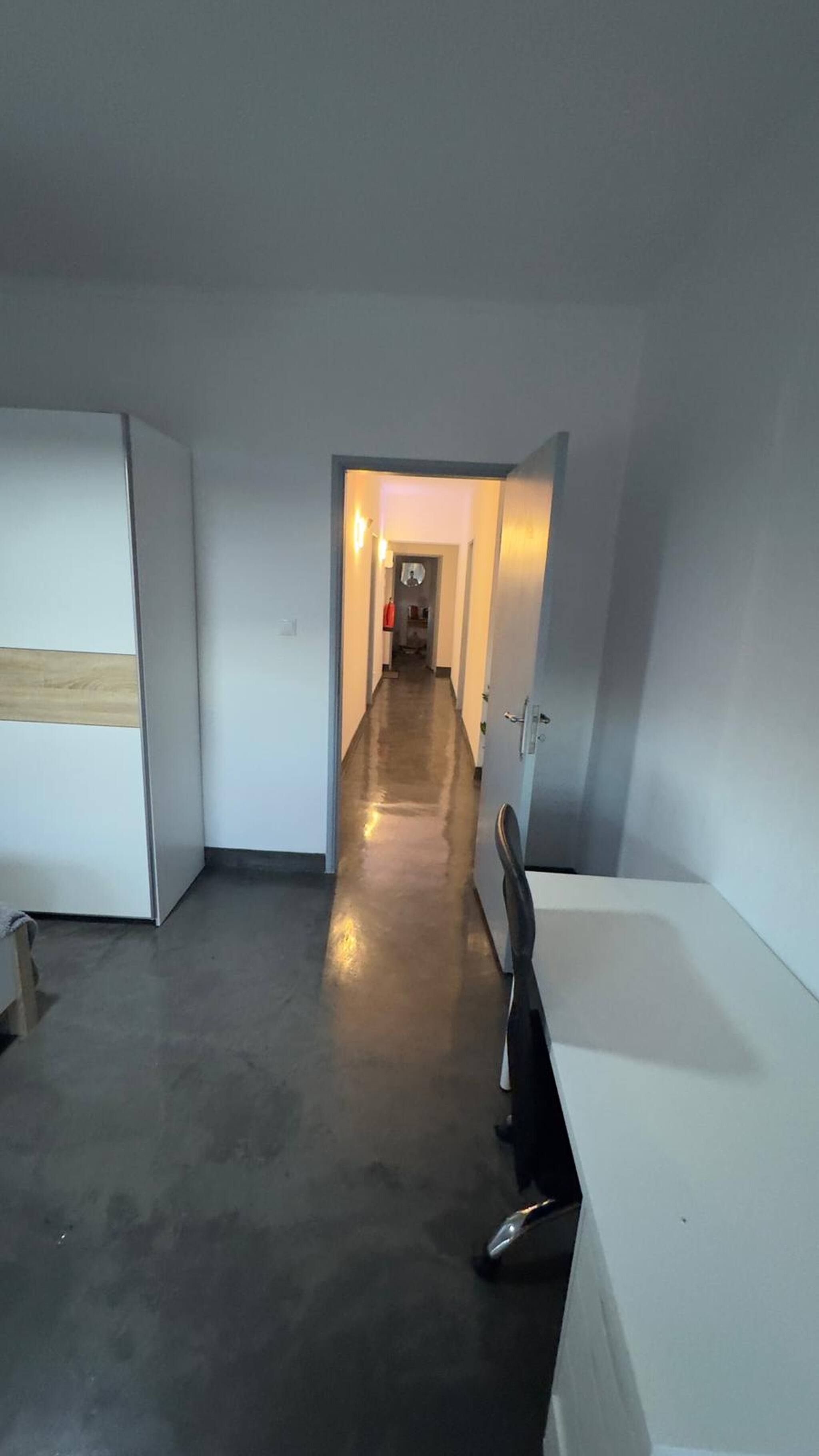 Um corredor com piso lustroso que termina em uma porta.