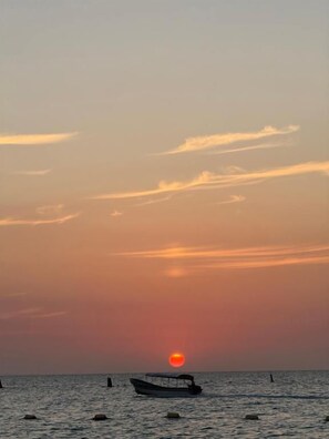 Um pôr do sol sobre o oceano, com um barco e boias.