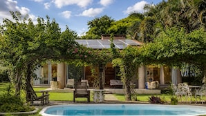 Um imóvel residencial com piscina, área de estar externa e vegetação exuberante.