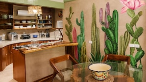 Cozinha com área de bar, armários de madeira e um mural com cactos na parede.