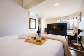 Quarto de hotel com cama, televisão, minibar e janela.