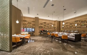 Interior de restaurante moderno com chão de mármore, assentos laranja e prateleiras de madeira com objetos decorativos.