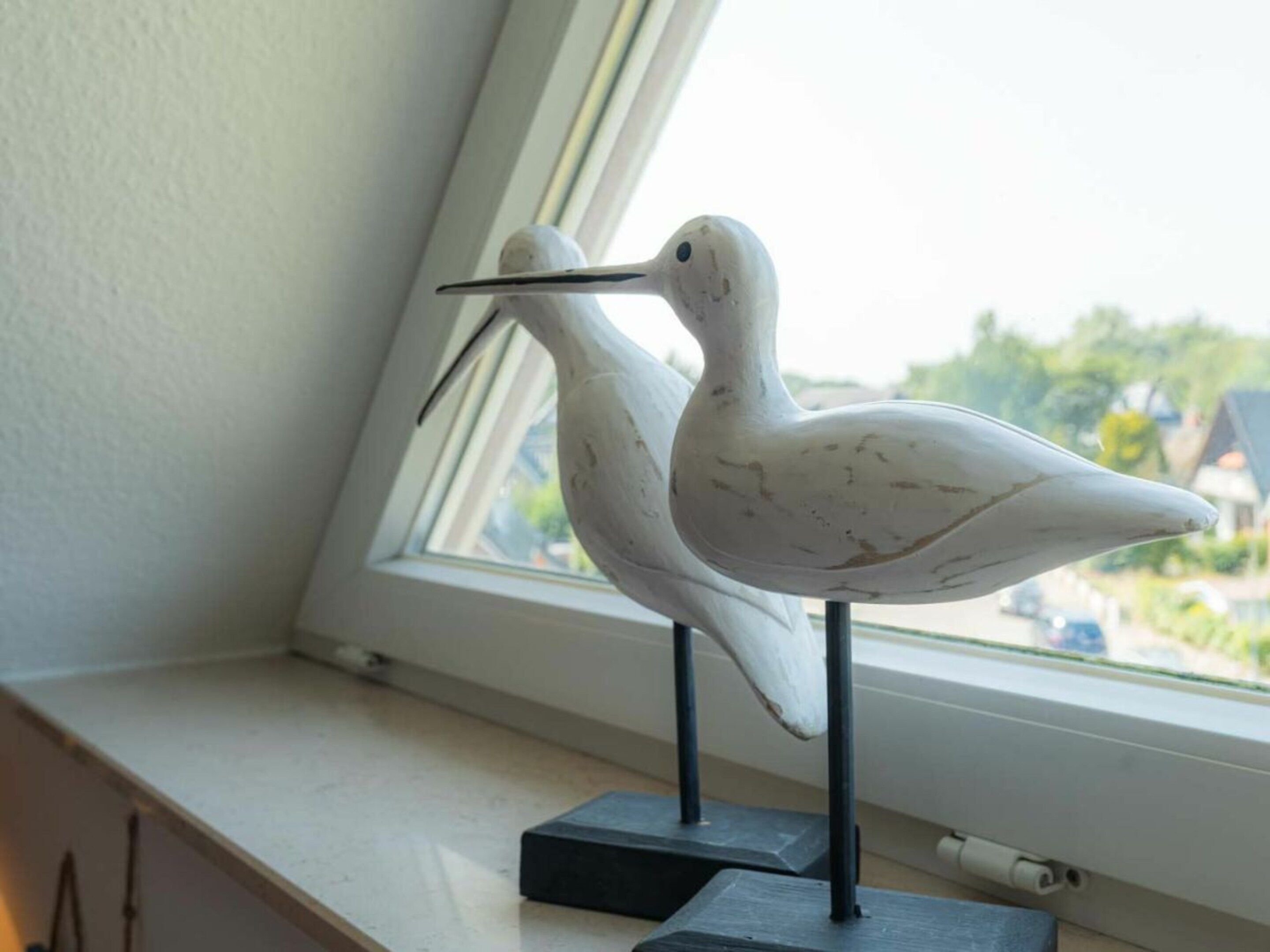 Uma escultura em forma de pássaro em um peitoril de janela.