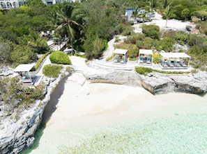 Propriedade costeira com praia rochosa, águas cristalinas e vários espaços de estar ao ar livre com guarda-sóis.