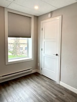 Um quarto com janela, porta e radiador.