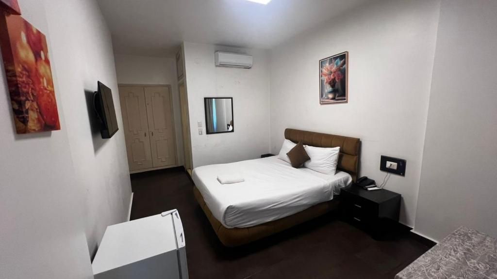 Quarto de hotel com cama, mesa de cabeceira e televisão na parede.