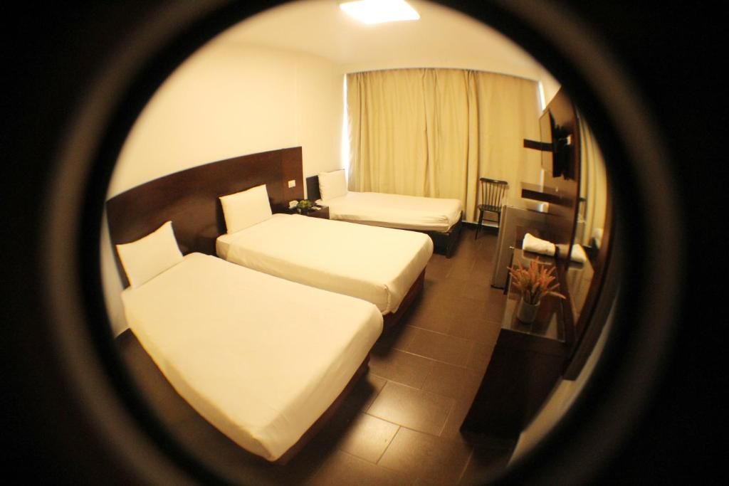 Quarto de hotel com duas camas, uma escrivaninha e uma cadeira.