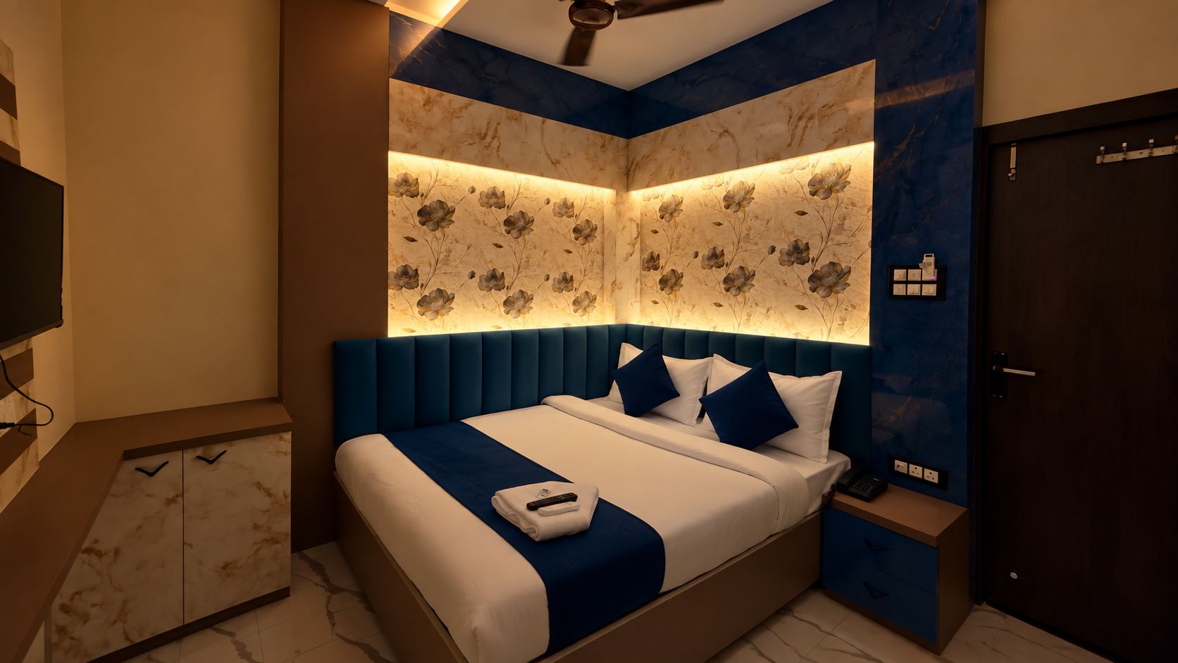 Quarto moderno com cama grande, cabeceira com iluminação embutida, mesa de cabeceira com telefone e guarda-roupa com espelho.