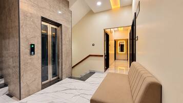 Um hall de hotel moderno, com piso de mármore, um sofá e um elevador.