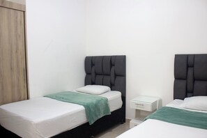 Quarto com duas camas, cada uma com cabeceira, mesa de cabeceira e gaveta.