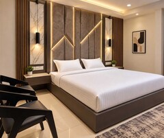 Quarto moderno com uma cama grande, mesas de cabeceira, escrivaninha e uma cadeira.