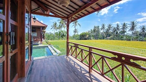 Um deck de madeira com piscina e vista para um campo de arroz.