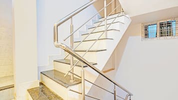 Escadaria em espiral com corrimão de metal e uma janela com grades.