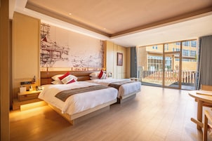 Quarto de hotel com uma cama grande, mesas de cabeceira, escrivaninha e vista para o exterior.