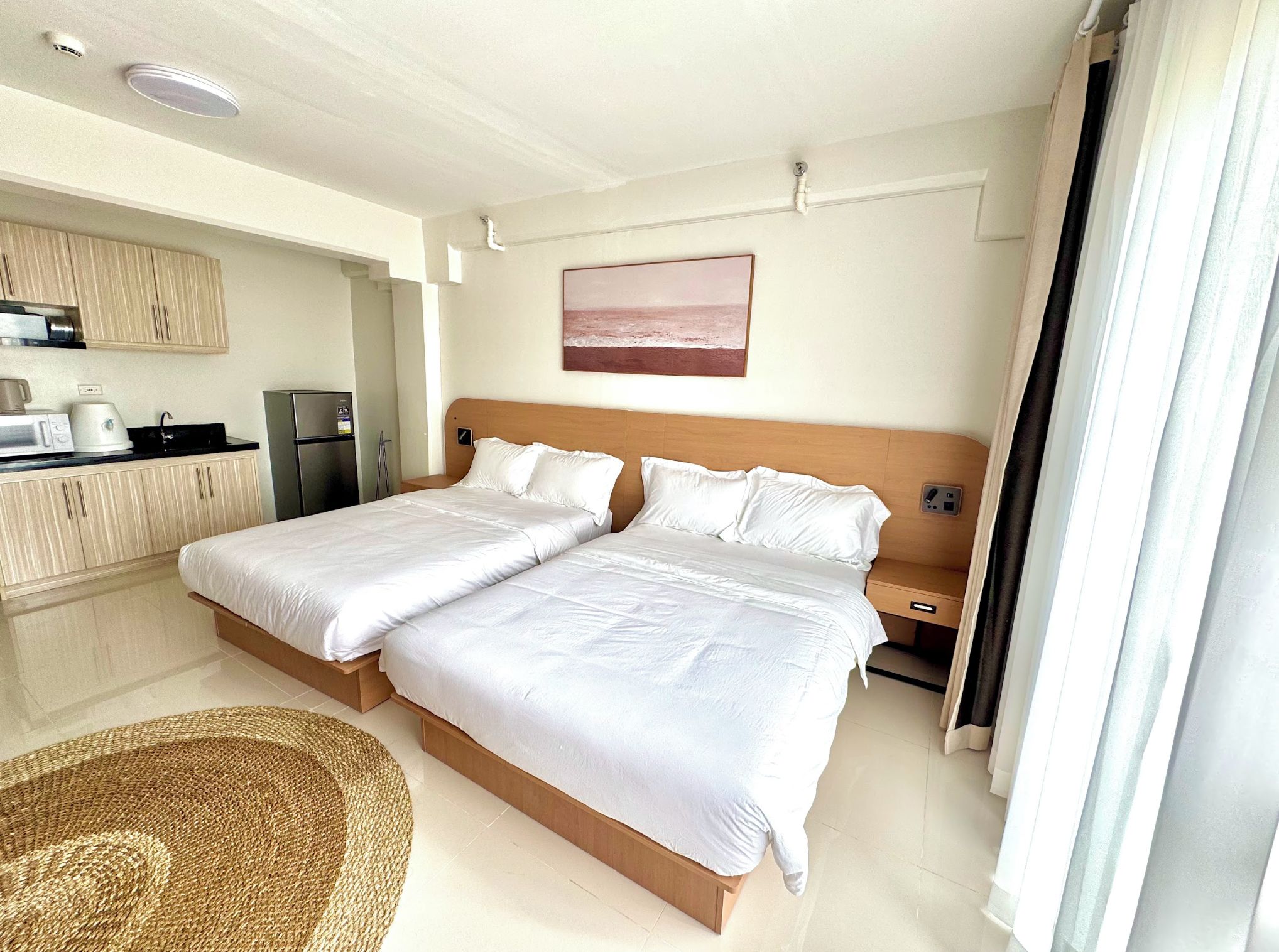 Quarto de hotel com cama de casal, cozinha compacta e vista para a praia.