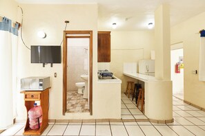 Casa de banho compacta com sanita, lavatório e televisão fixada na parede.