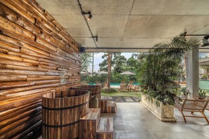 Paredes de toras de madeira, um barril de madeira e um espaço de estar com cadeiras e uma mesa.
