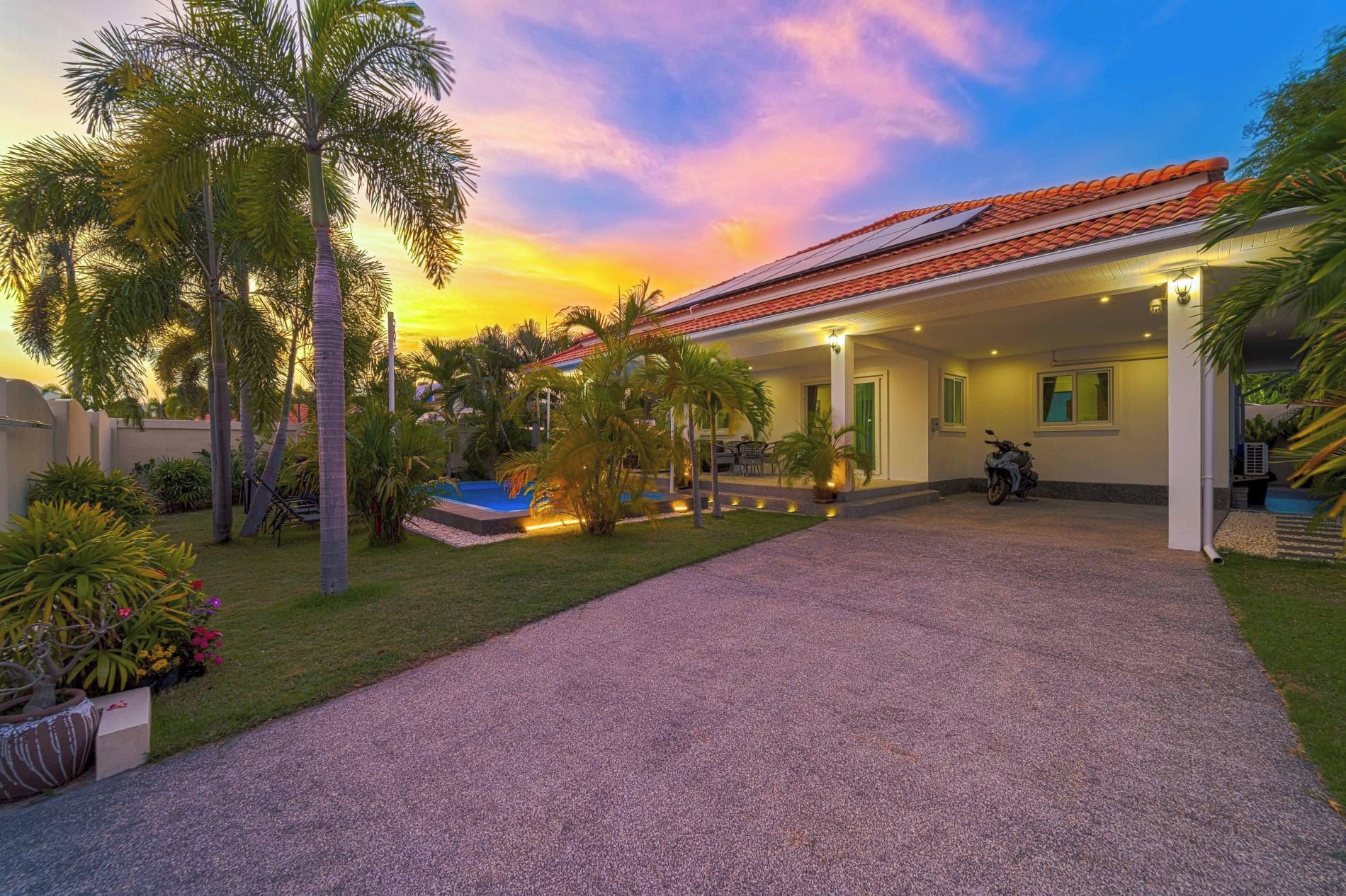 Uma casa com varanda coberta, piscina e entrada com calçada.