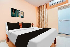 Quarto de hotel com cama, janela com cortinas e obra de arte pendurada na parede.