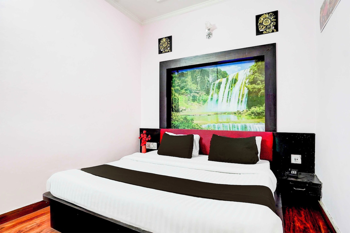 Quarto com cama grande, televisão na parede e parede de destaque vermelha.