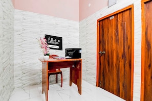 Um quarto com escrivaninha de madeira, impressora e aviso indicando que é um quarto de serviço da empresa.
