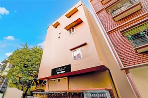 Um edifício de vários andares com fachada plana, placa de empresa visível e janela com grade de metal.