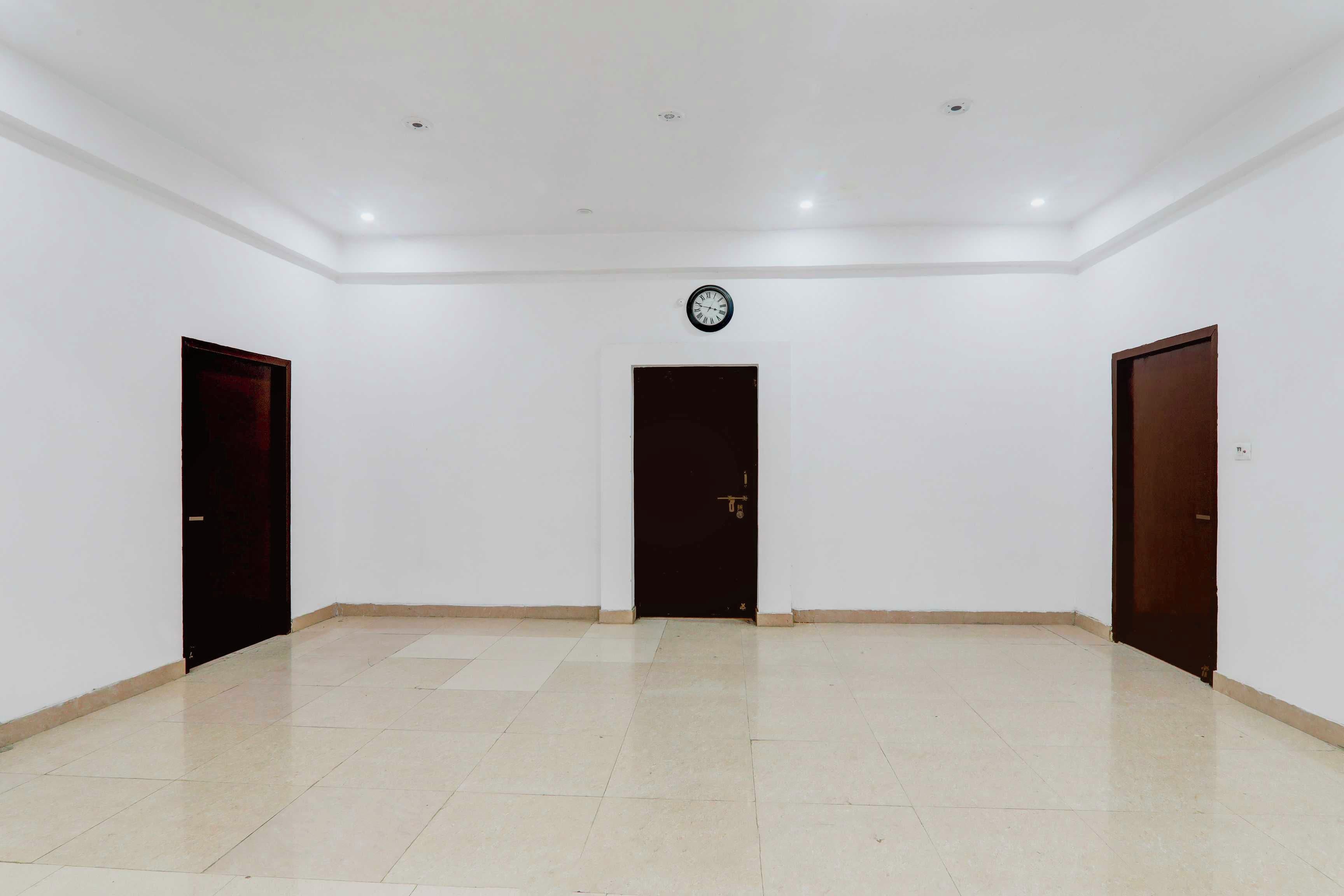 Um quarto com três portas, um relógio na parede e piso de azulejos.