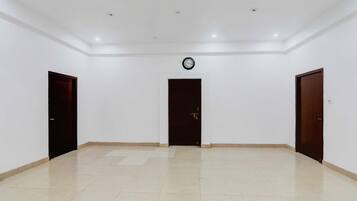Um quarto com três portas, um relógio na parede e piso de azulejos.