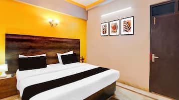 Quarto de hotel com uma cama grande, cabeceira de madeira, mesa de cabeceira com abajur e uma porta.