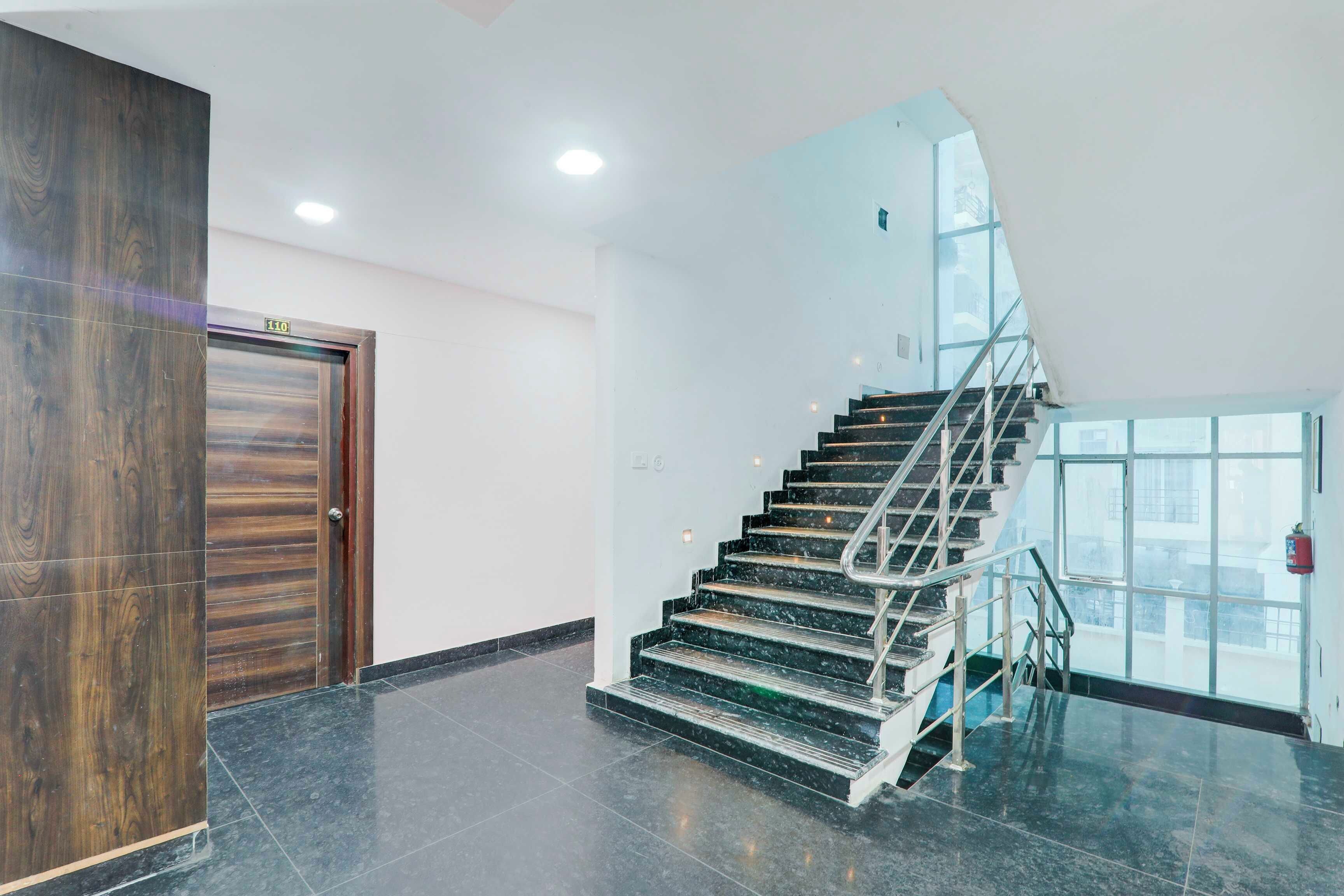 Interior moderno com escada, porta de madeira e parede de vidro.