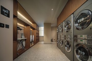 Uma lavanderia moderna com várias máquinas de lavar, uma área de secagem e um espaço de armazenamento bem organizado com prateleiras.