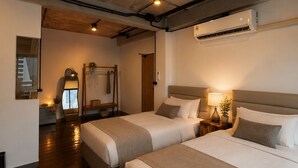 Quarto de hotel com duas camas, um espelho grande e um aparelho de ar condicionado.