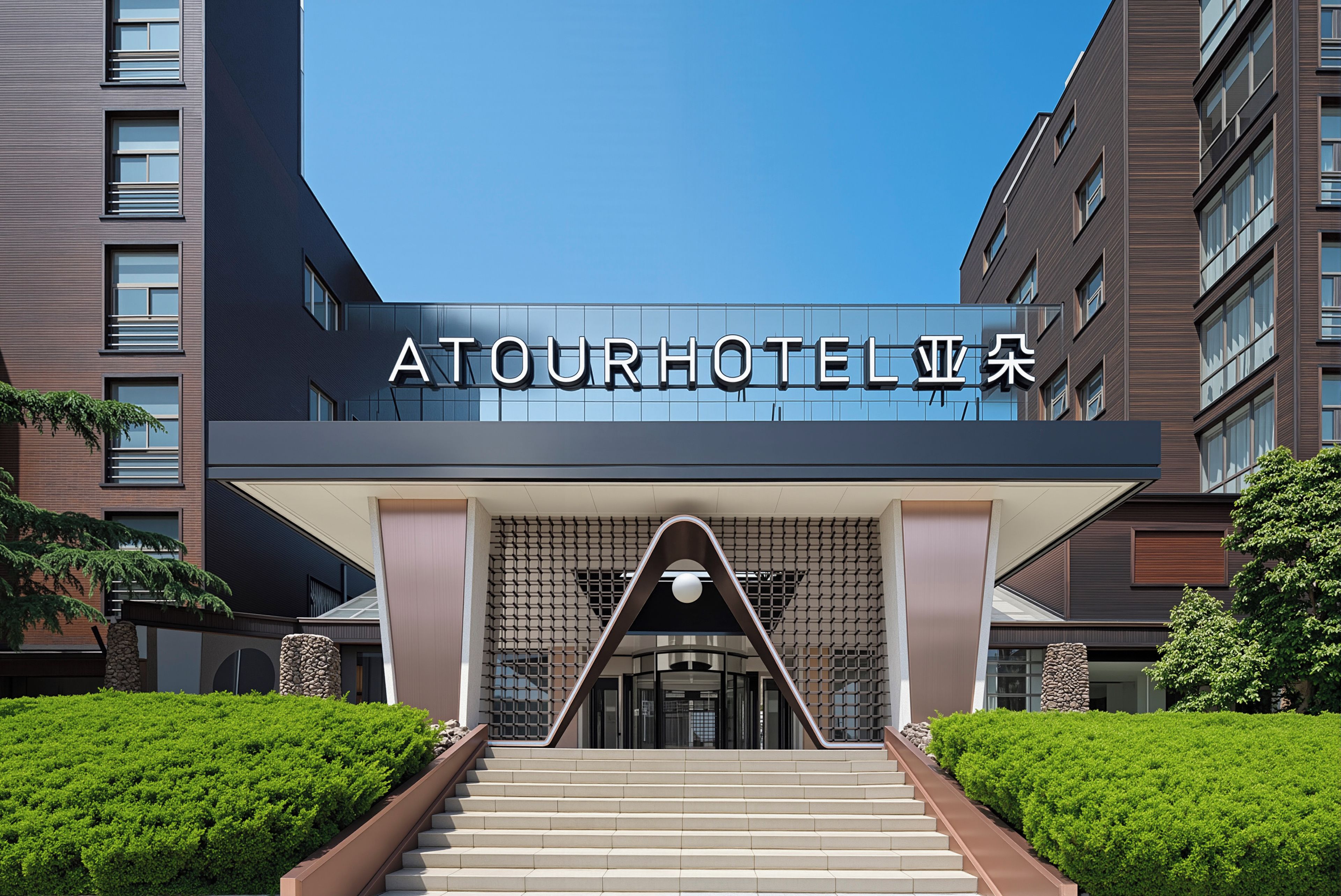 Entrada moderna de hotel com céu claro, uma placa com o texto 'ATOURHOTEL' e uma escadaria que leva à entrada.