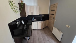 Uma cozinha compacta com bancada preta, armários de madeira e radiador.