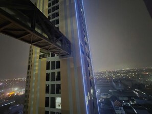 Um edifício alto com fachada azul iluminada e uma ponte visível.