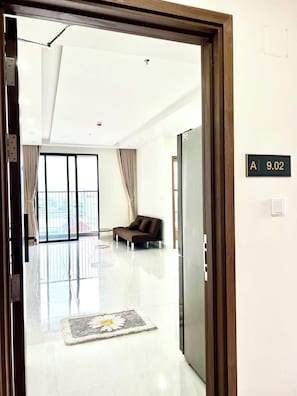 Quarto de hotel moderno com uma grande porta de vidro deslizante que dá para uma varanda, um sofá e um tapete pequeno.