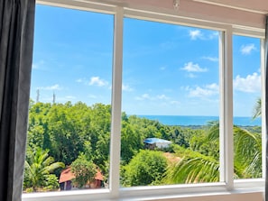 Uma janela ampla com vista para uma paisagem verde exuberante e um céu azul límpido.