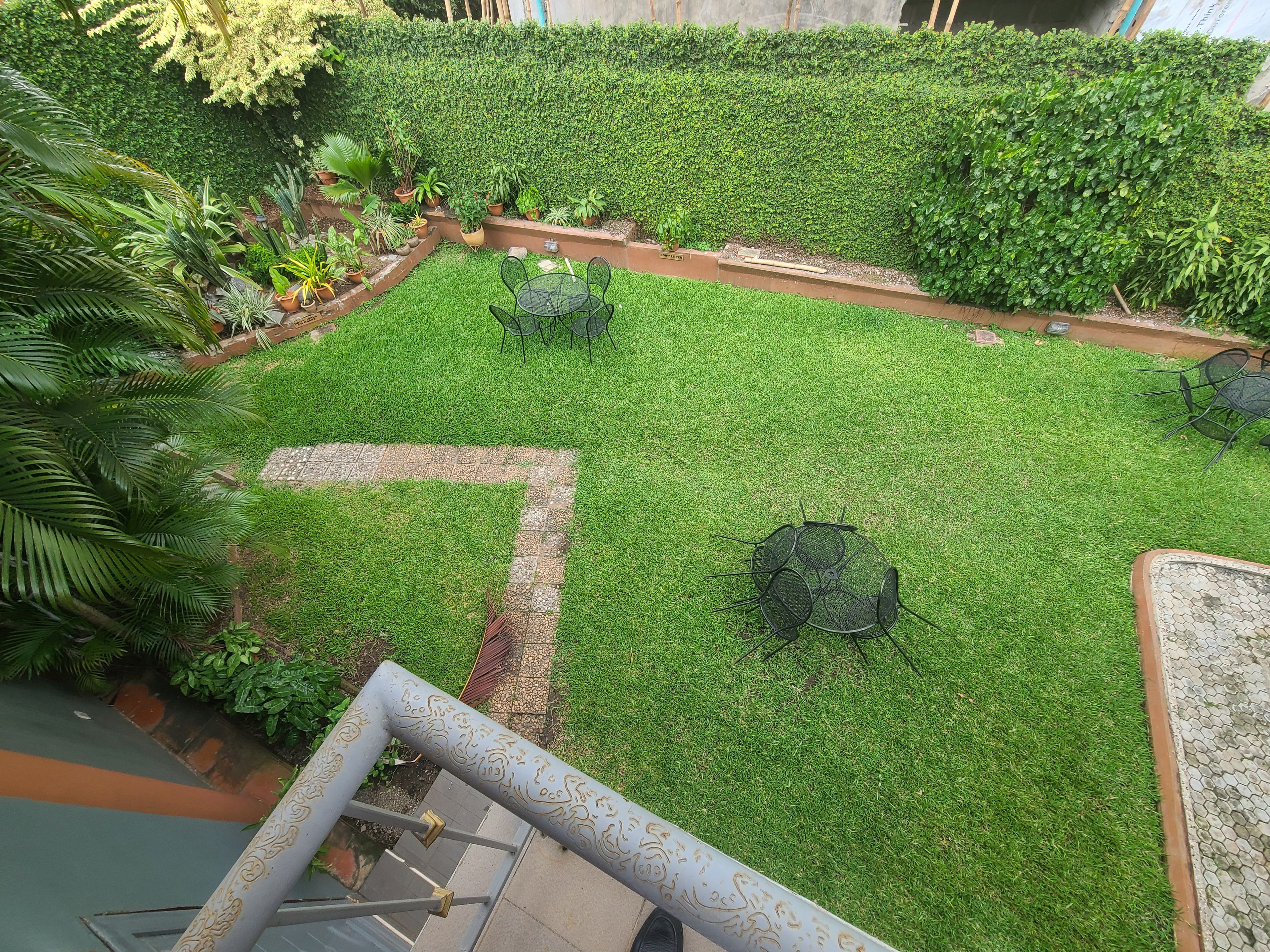 Um jardim bem cuidado com gramado, plantas em vasos e móveis de exterior.