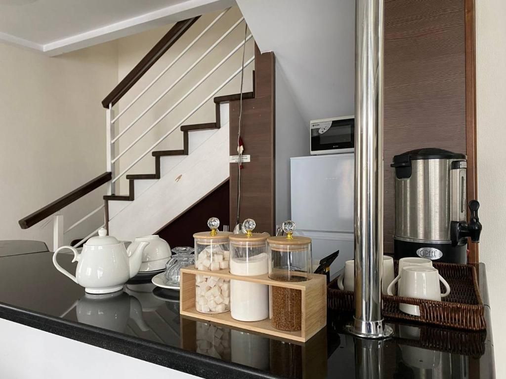 Uma bancada de cozinha com cafeteira, bule e potes de açúcar e farinha.