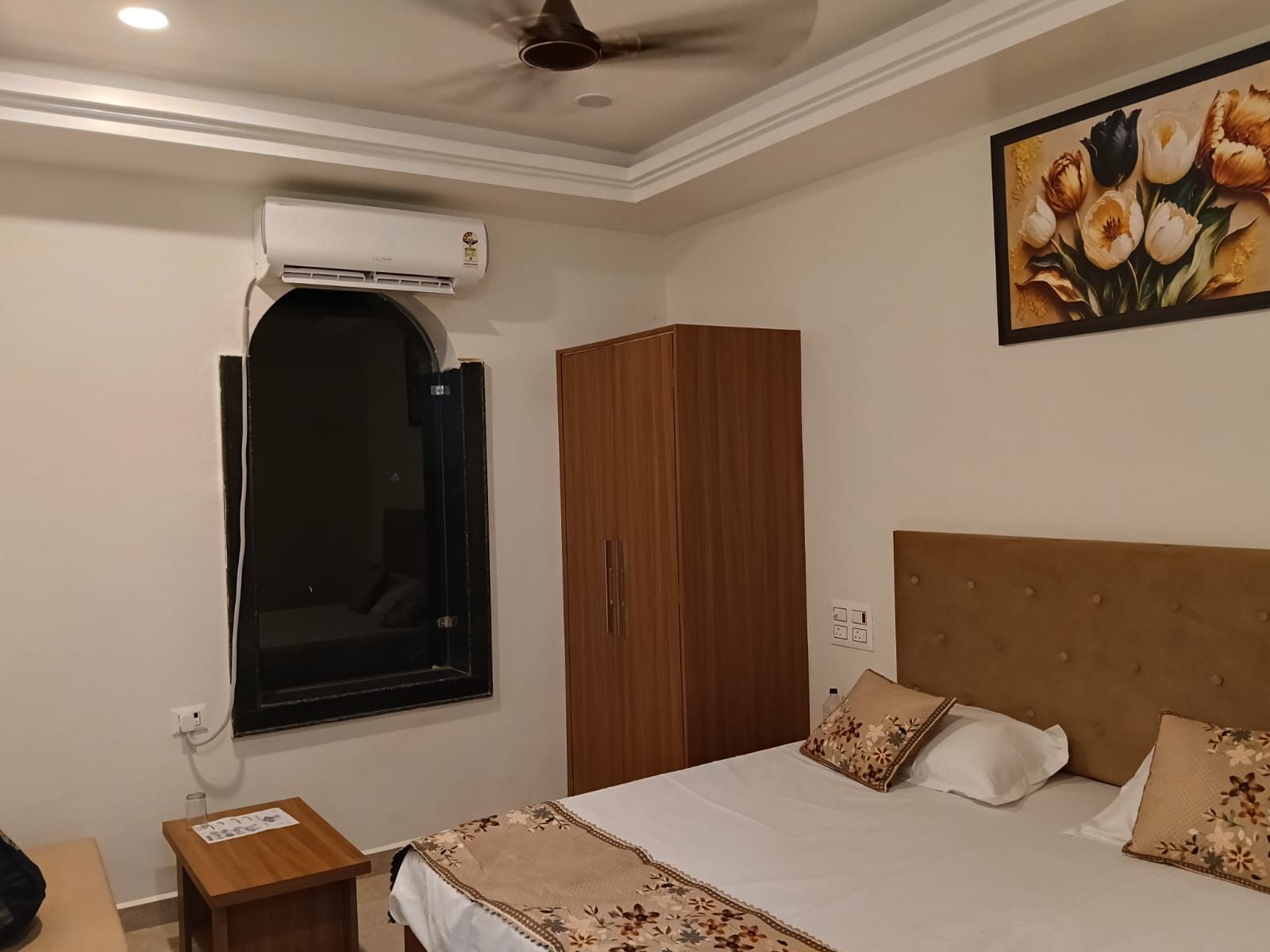 Quarto com cama, guarda-roupa, ar condicionado, janela e um quadro na parede.