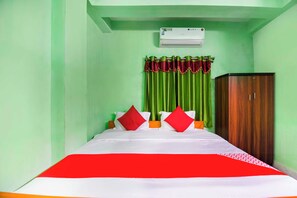 Quarto de hotel com cama, guarda-roupa e ar condicionado.