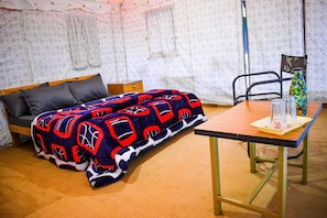 Quarto com cama, mesa e cadeira. Parede com padrão e janela com cortinas.