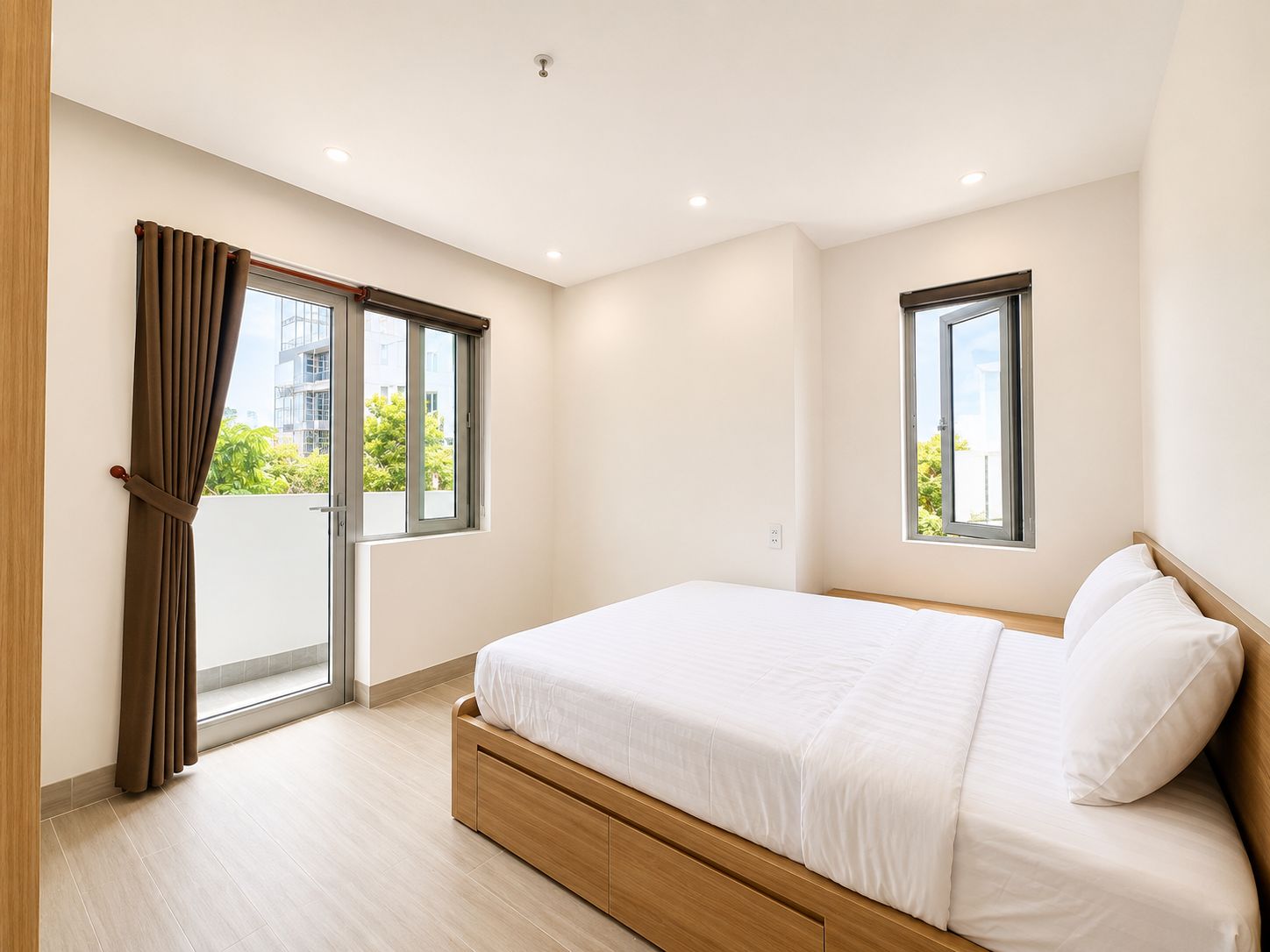 Quarto moderno com uma cama grande, portas de vidro deslizantes e vista para o verde lá fora.